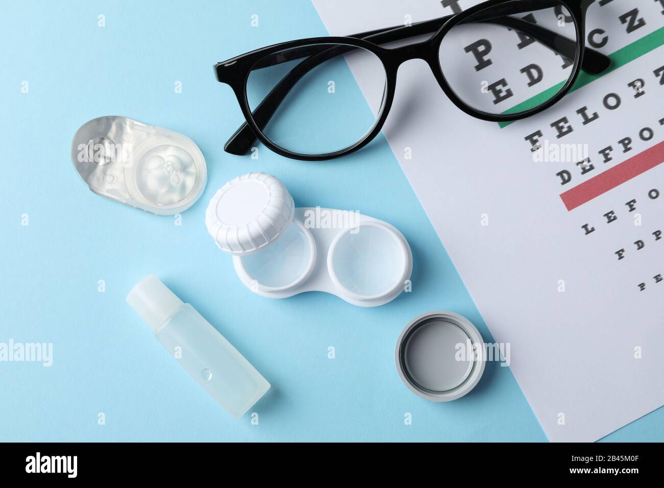 Glasses, contact lenses and eye test chart on blue background, top view ...