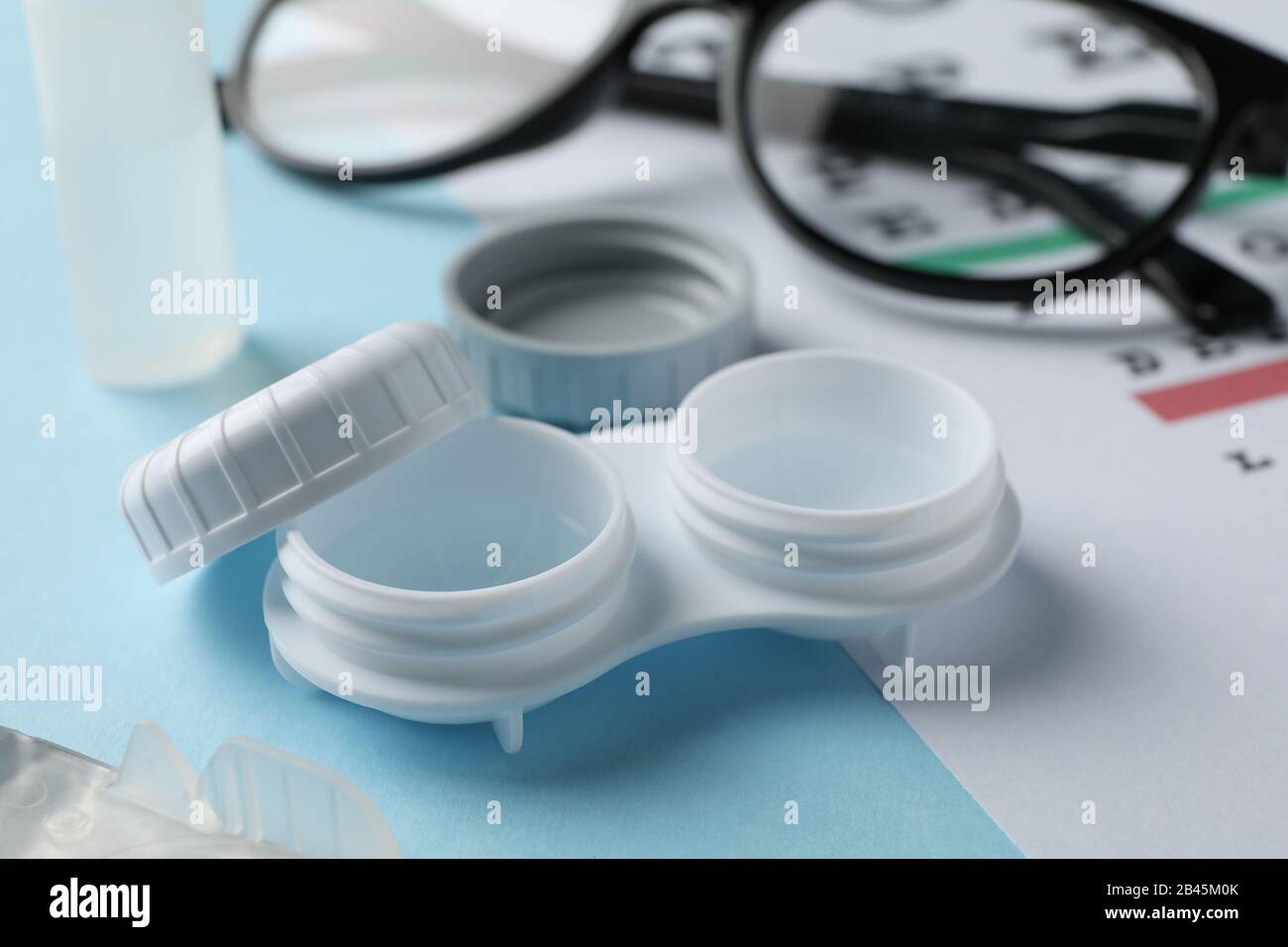 Glasses, contact lenses and eye test chart on blue background, close up ...