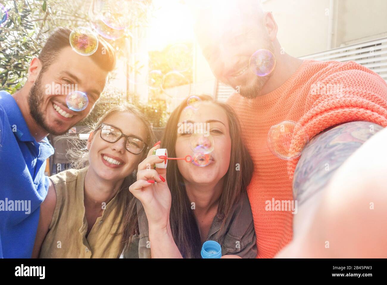 Happy friends taking snapshot selfie with mobile phone while throwing ...