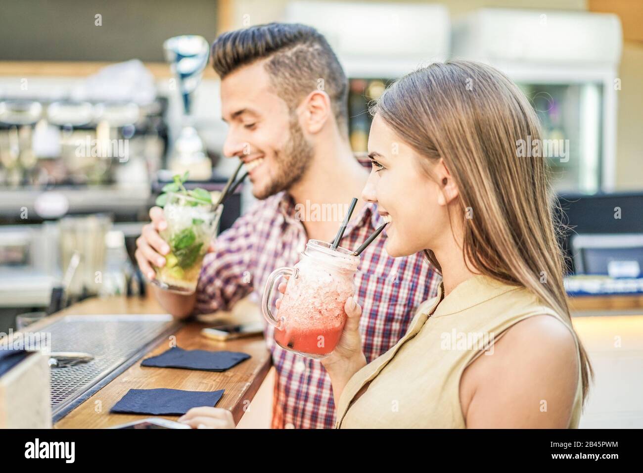 Young cheerful couple toasting cocktails in miami lounge disco bar ...