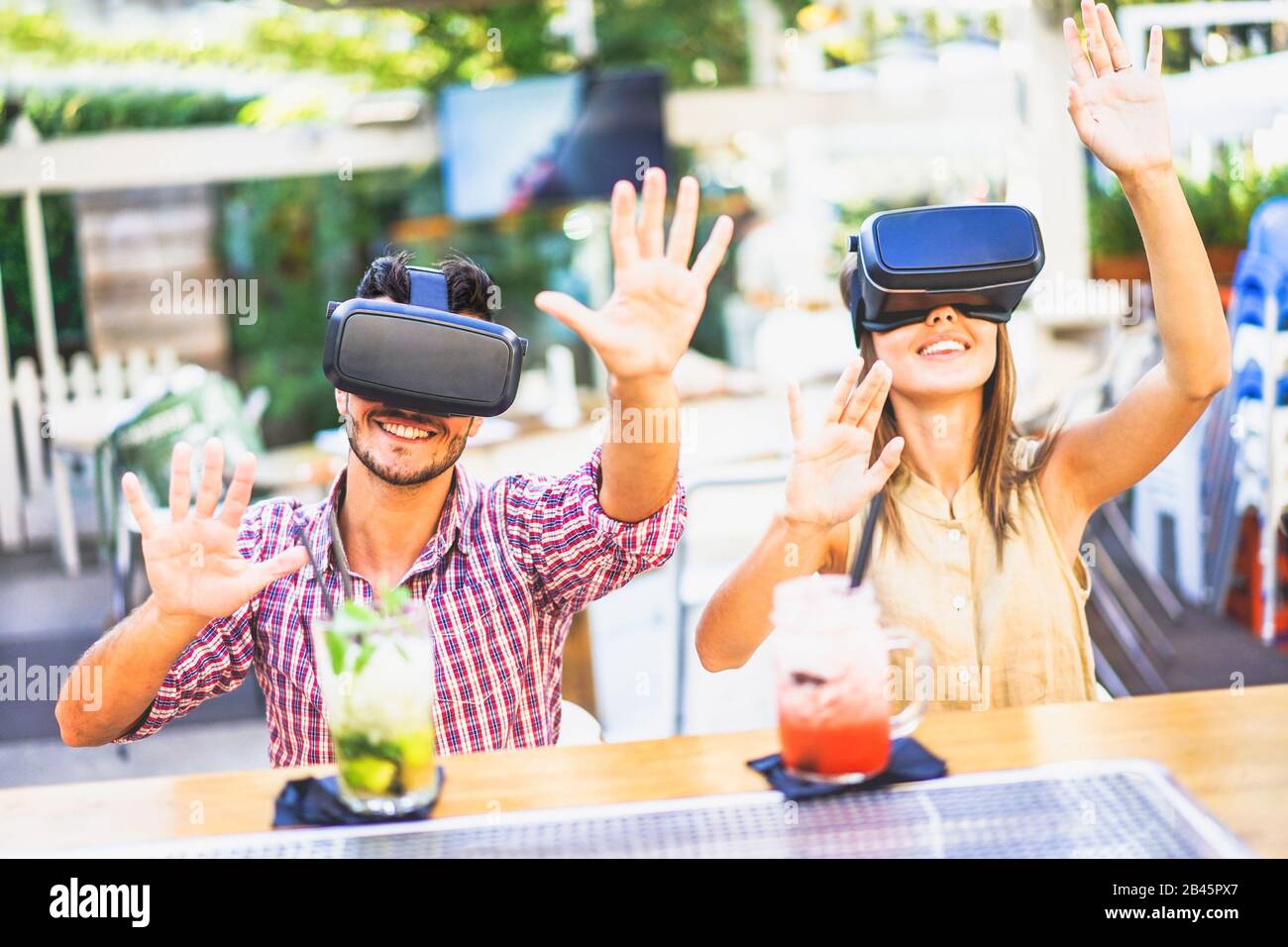 Amazed friends looking in VR goggles and gesturing with hands in ...