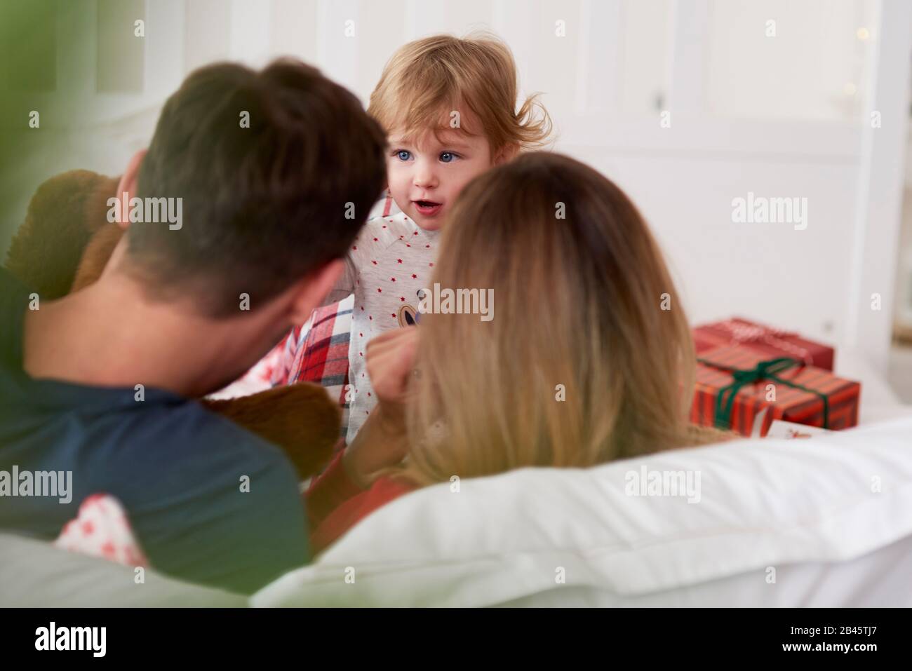 Rear view of baby with parents in bed Stock Photo - Alamy