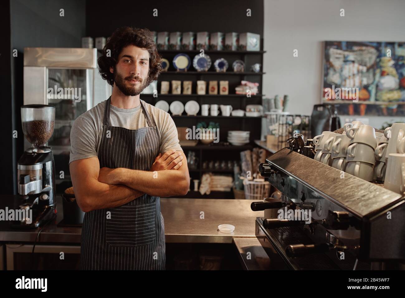 Male business owner behind the counter of a coffee shop with folded ...