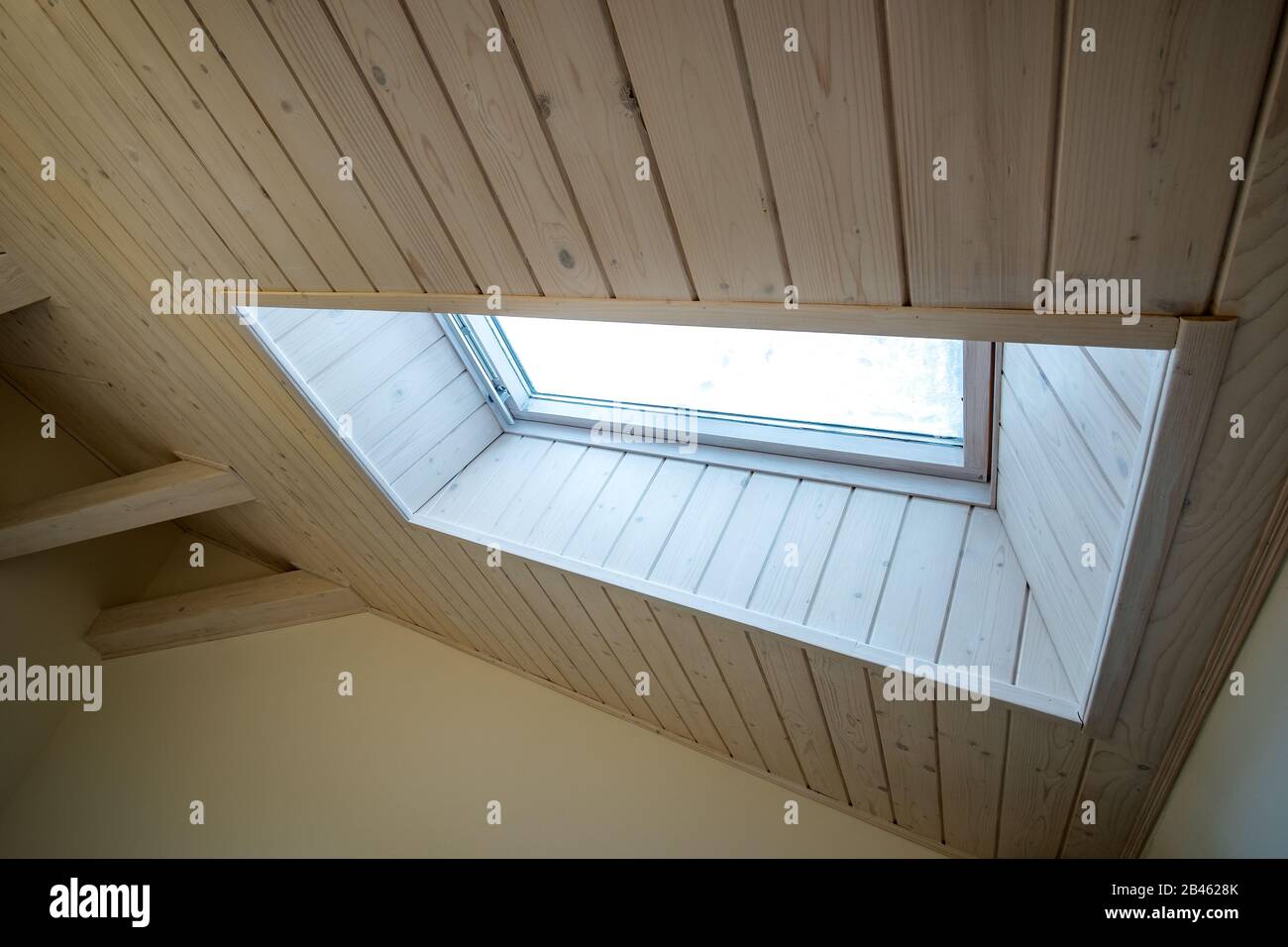 Wooden ceiling in a contemporary mansard room with attic window ob ...