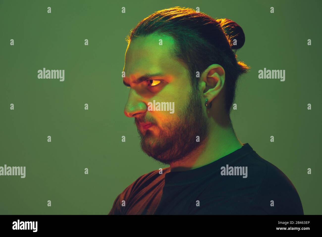 Portrait of a guy with colorful neon light on green studio background ...