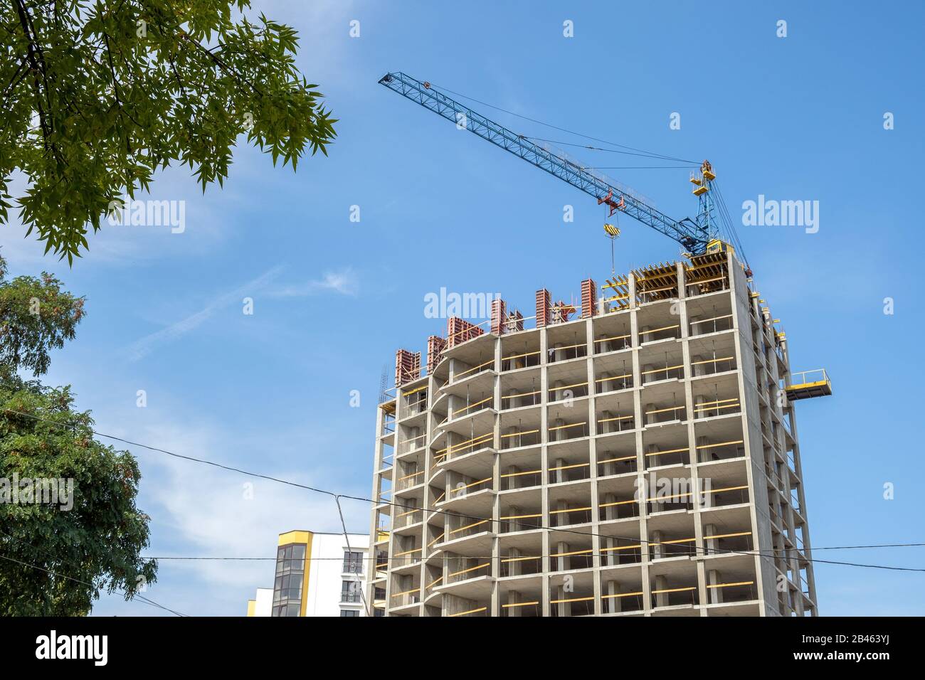 Concrete frame of tall apartment building under construction and tower ...