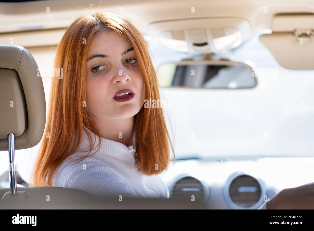 Young redhead woman driver driving a car backwards Stock Photo - Alamy