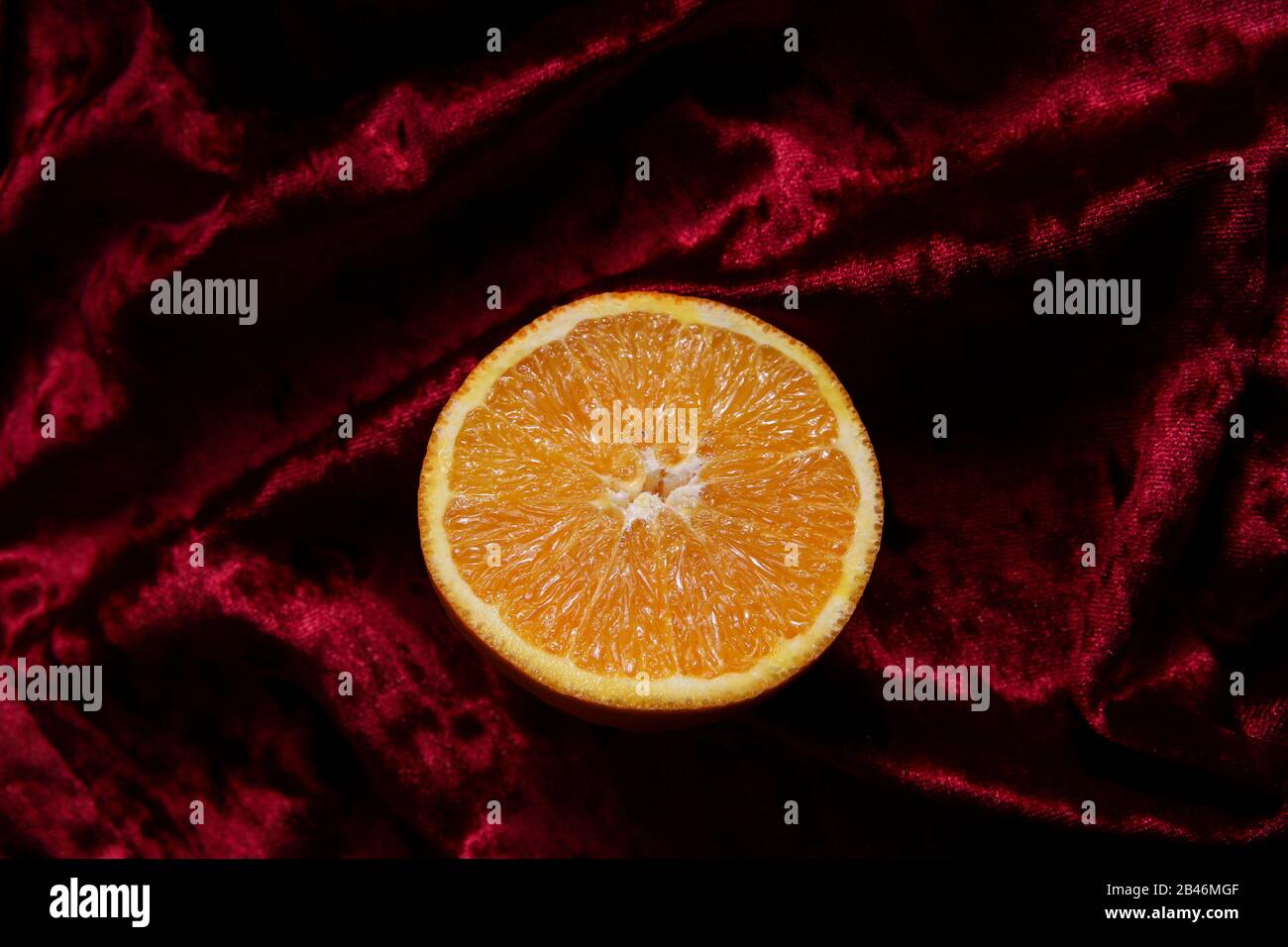 Half of orange on red velvet background. Citrus fruits still life ...