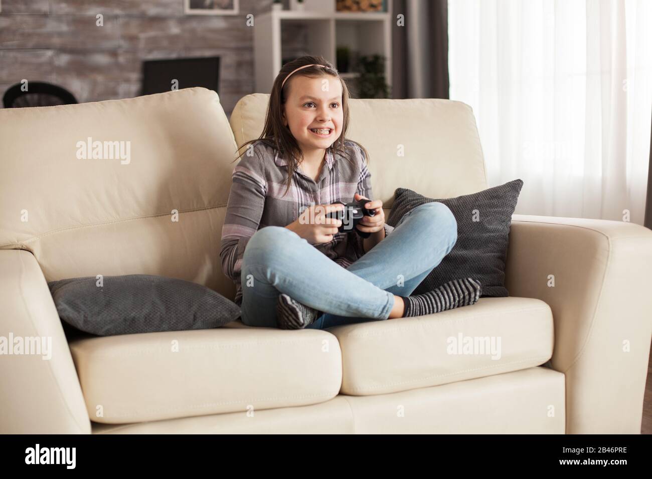 Focused little girl with braces playing video games using wireless ...