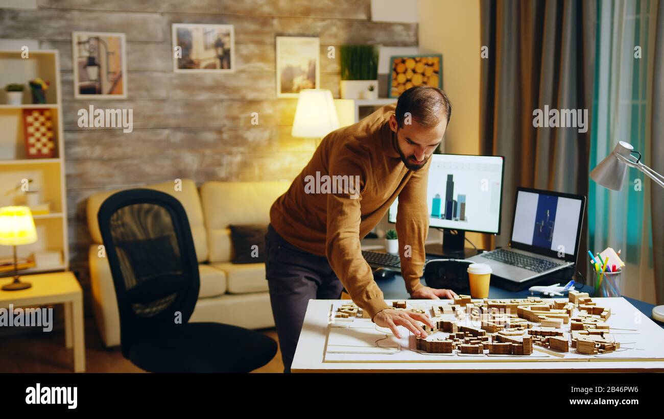 Architect working at night in his home office on a city development ...