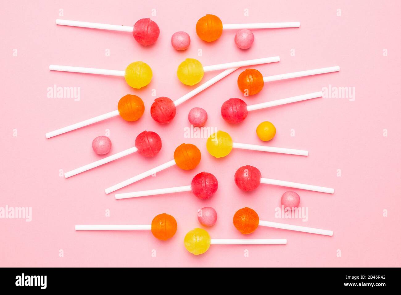 Pink, orange and yellow sweet candy lolipop on a pastel pink background ...