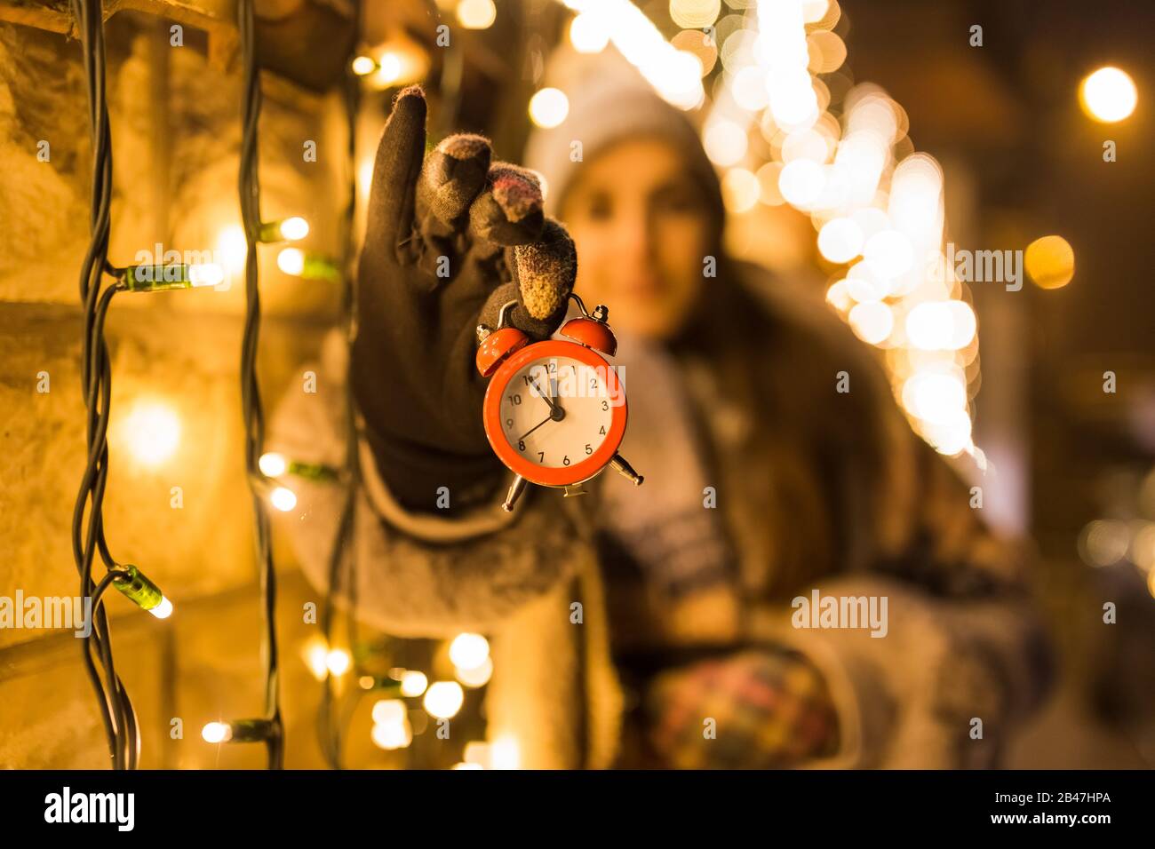 Young female showing alarm clock. Almost midnight time to celebrate ...