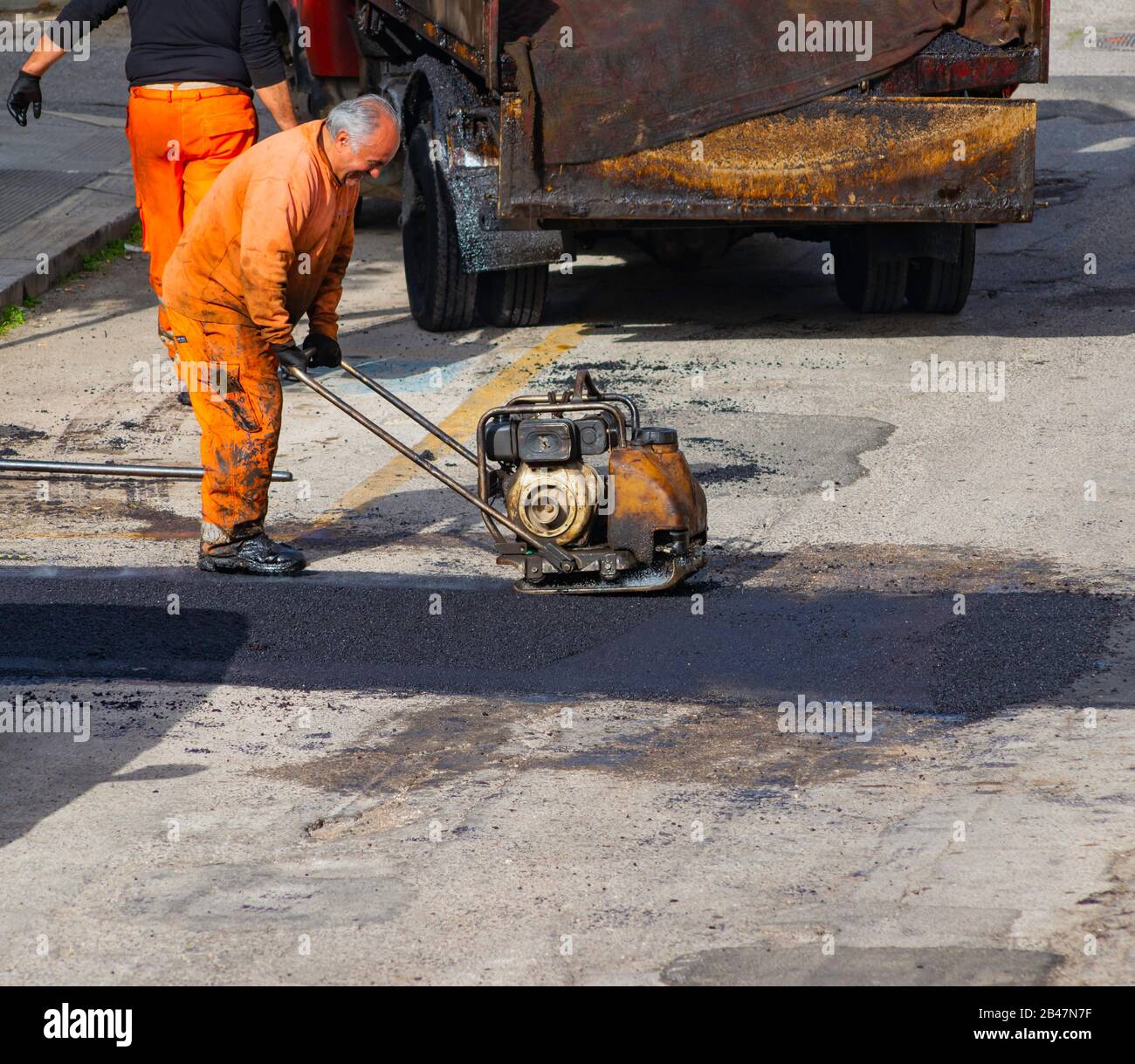 Compactor finishing the last phase of laying new asphalt to patch a ...