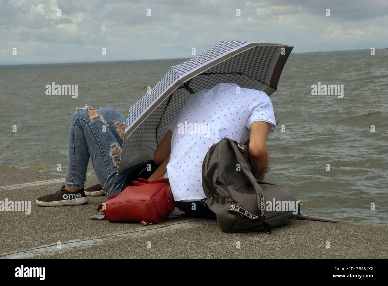 Young couple manila hugging under an umbrella, Promenade, Manila Bay ...