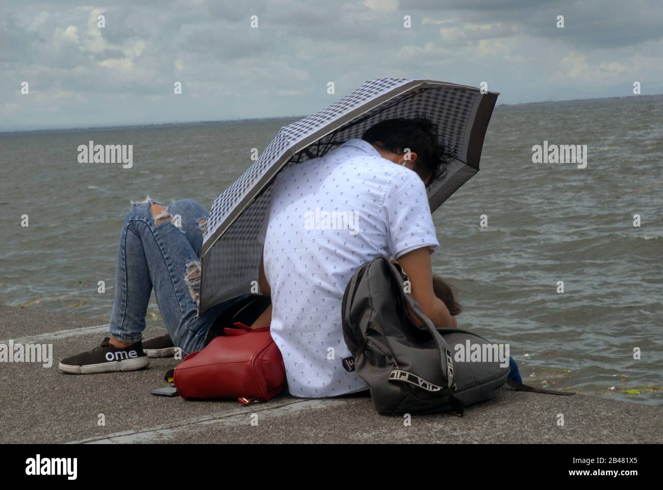 Young couple manila hugging under an umbrella, Promenade, Manila Bay ...