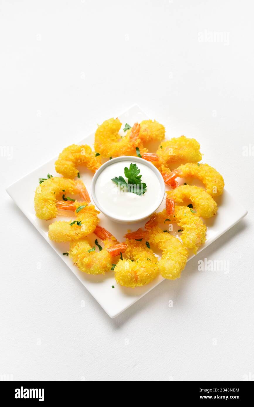 Deep fried breaded prawn with sauce on plate over white stone ...