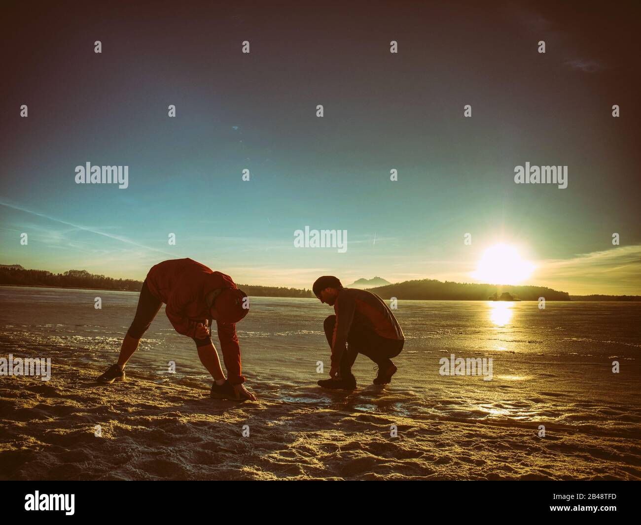 Woman and man stretching in winter nature before run. Two sports people ...