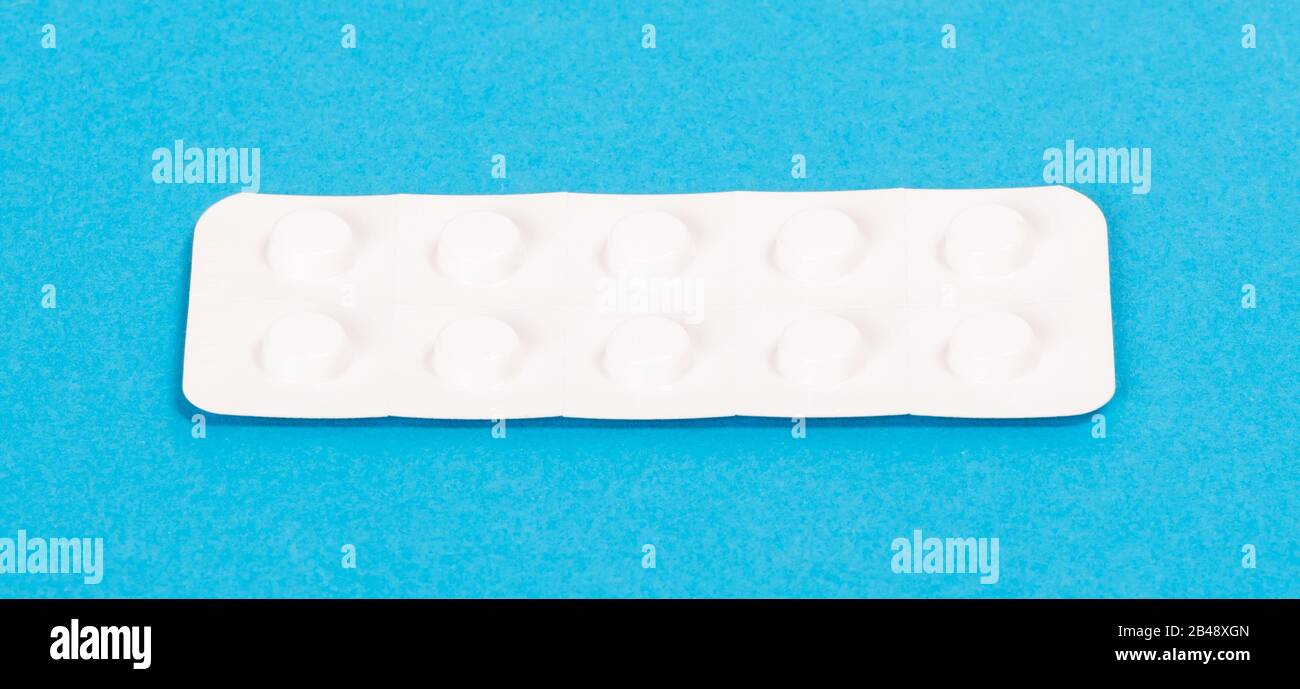 Pill strip isolated on a blue background Stock Photo - Alamy