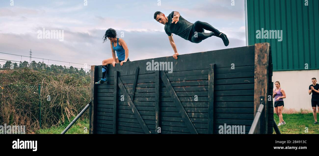 Participants in obstacle course climbing wall Stock Photo - Alamy