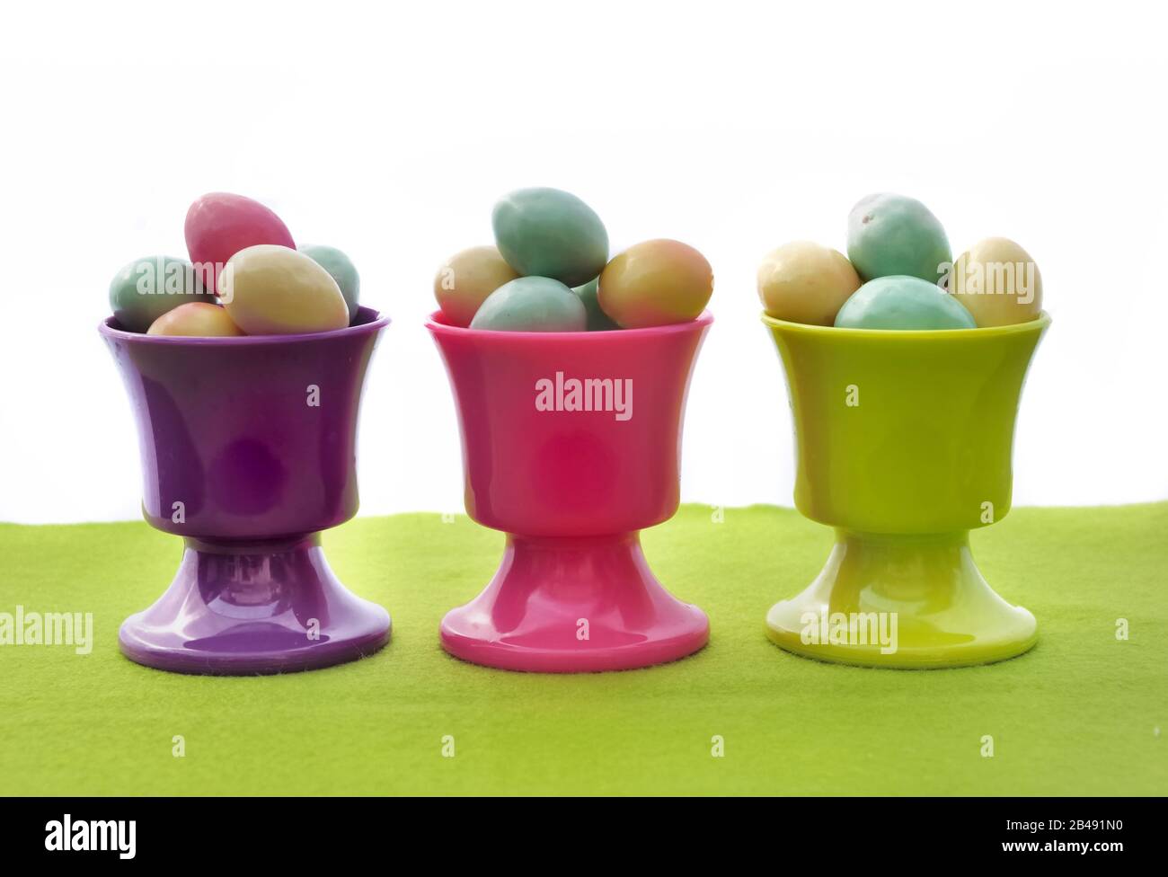 egg cups filled with small Easter eggs on green and white background ...