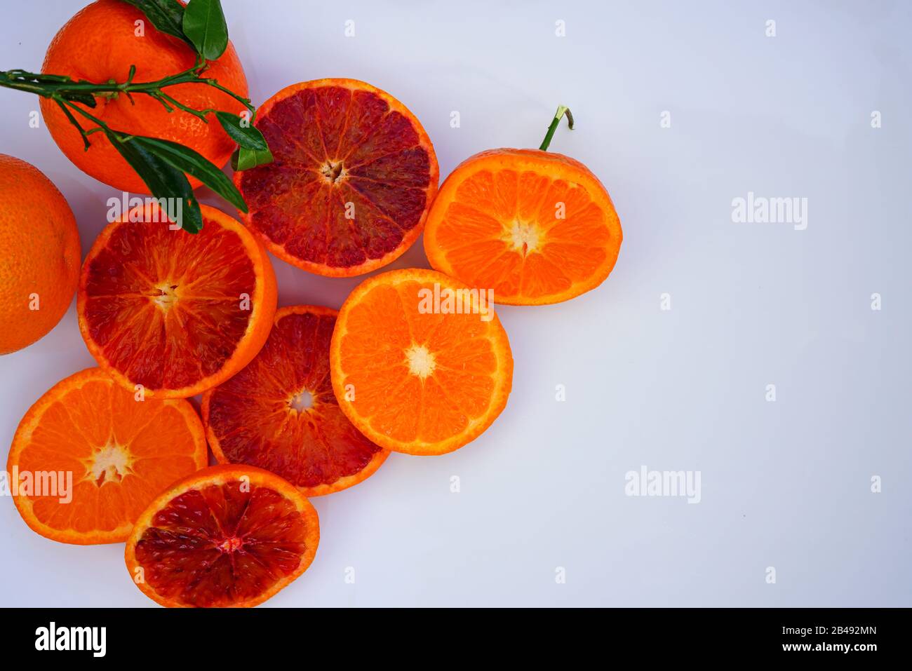 Platter of orange and mandarosa red clementines cut in half on a white ...