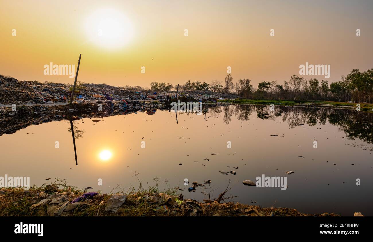 Polluted water and mountain large garbage pile and pollution at the sun ...