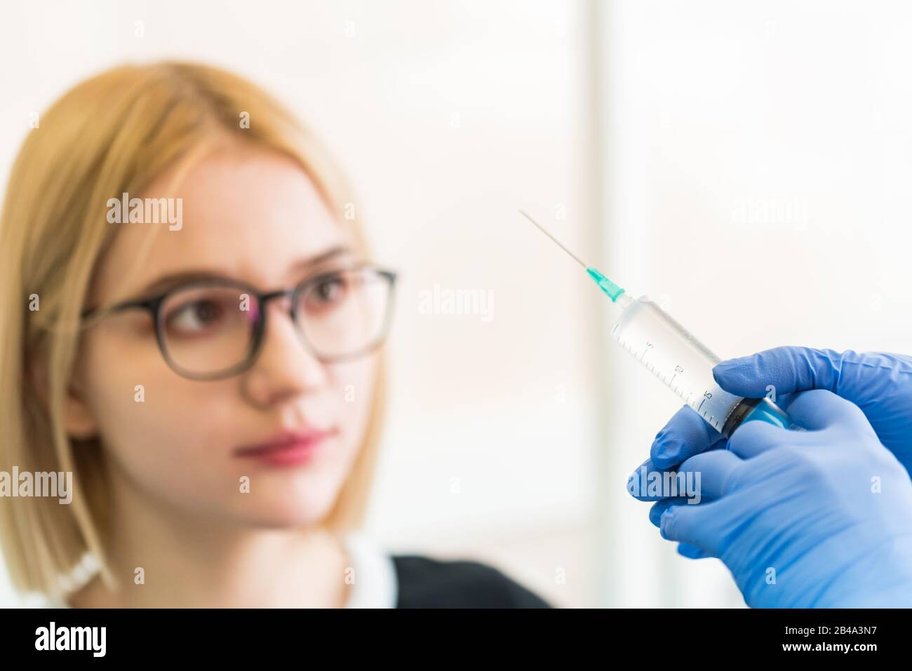 Fear of injections. Frightened girl looks at syringe needle during ...