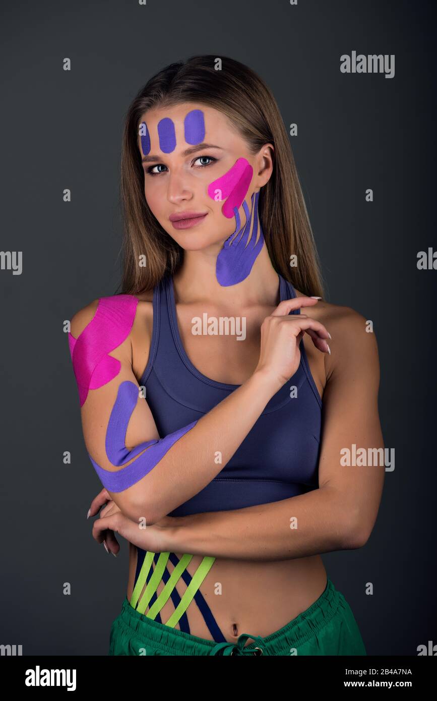 Woman shows kinesio tapes taped to her belly. Bright medical tape on ...