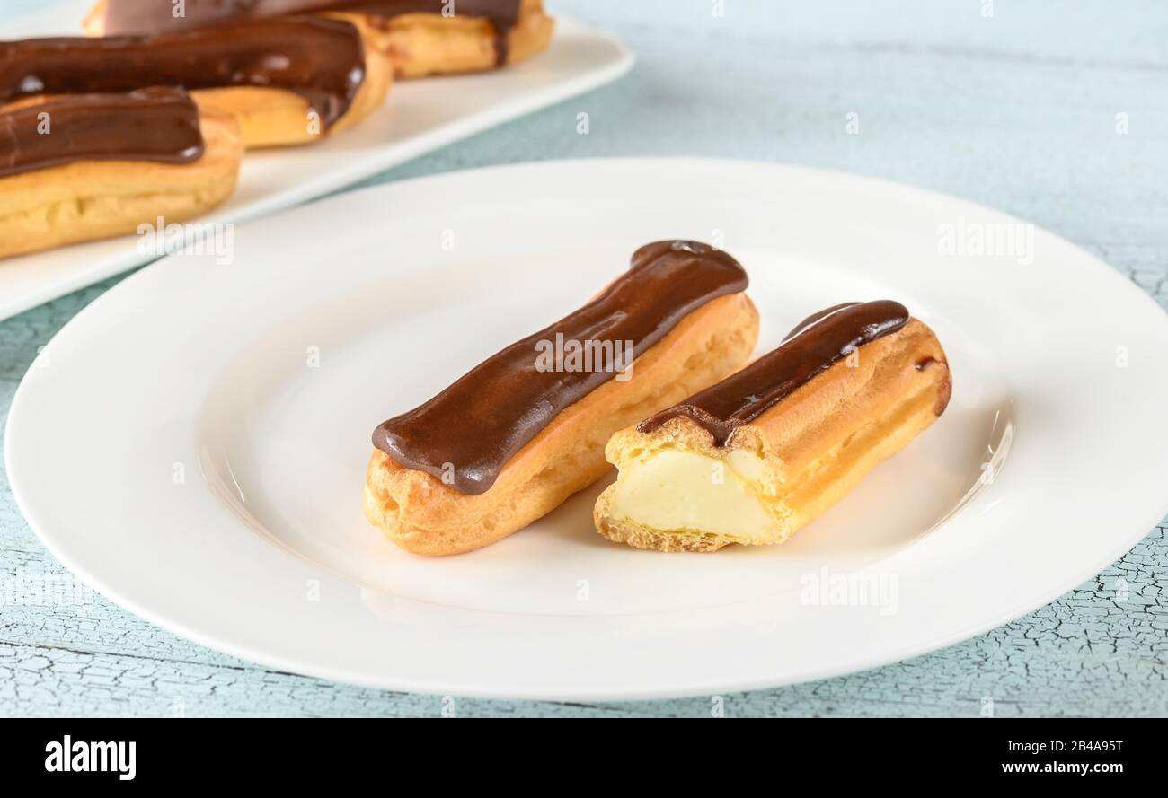 Eclairs with chocolate topping on serving plate Stock Photo - Alamy