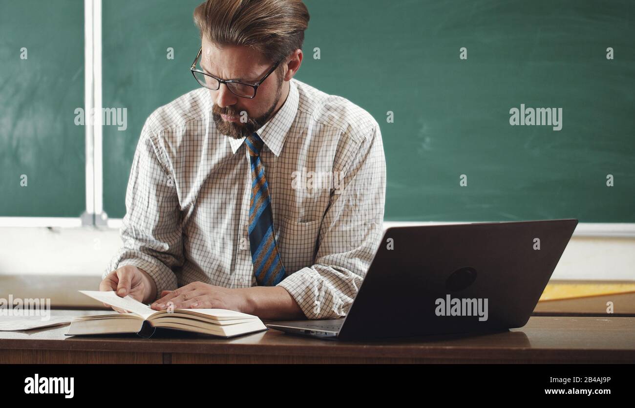 Teacher reading book in classroom Stock Photo - Alamy