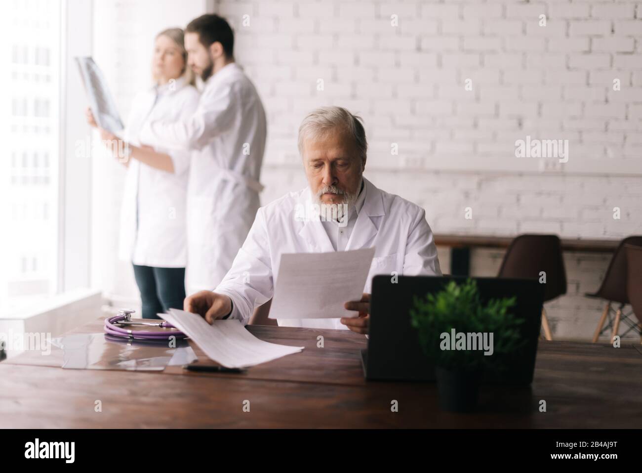 Adult doctor sits at his desk and studies his patients' documents Stock ...