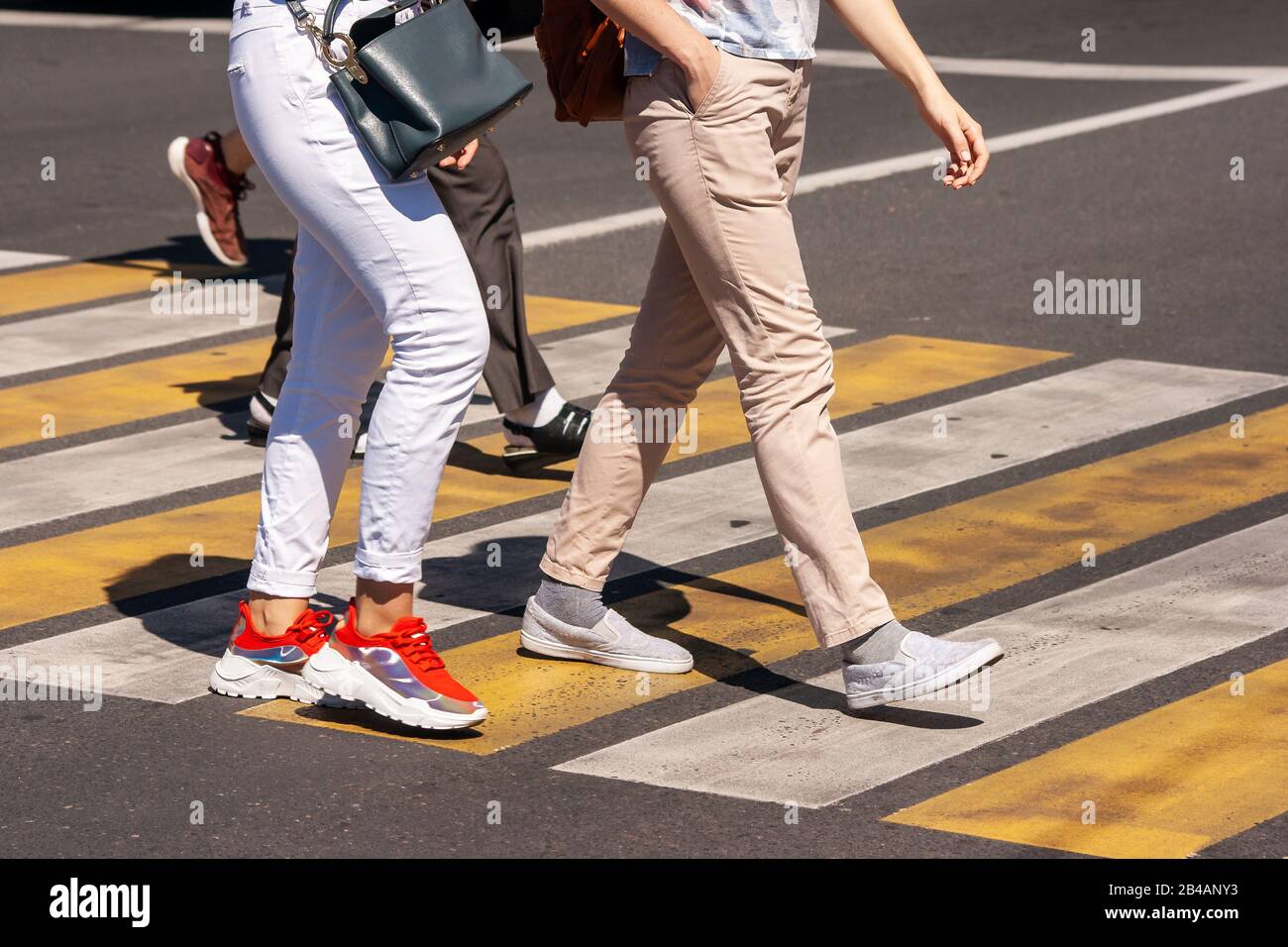 people crossing the street at pedestrian crossing on sunny summer day ...