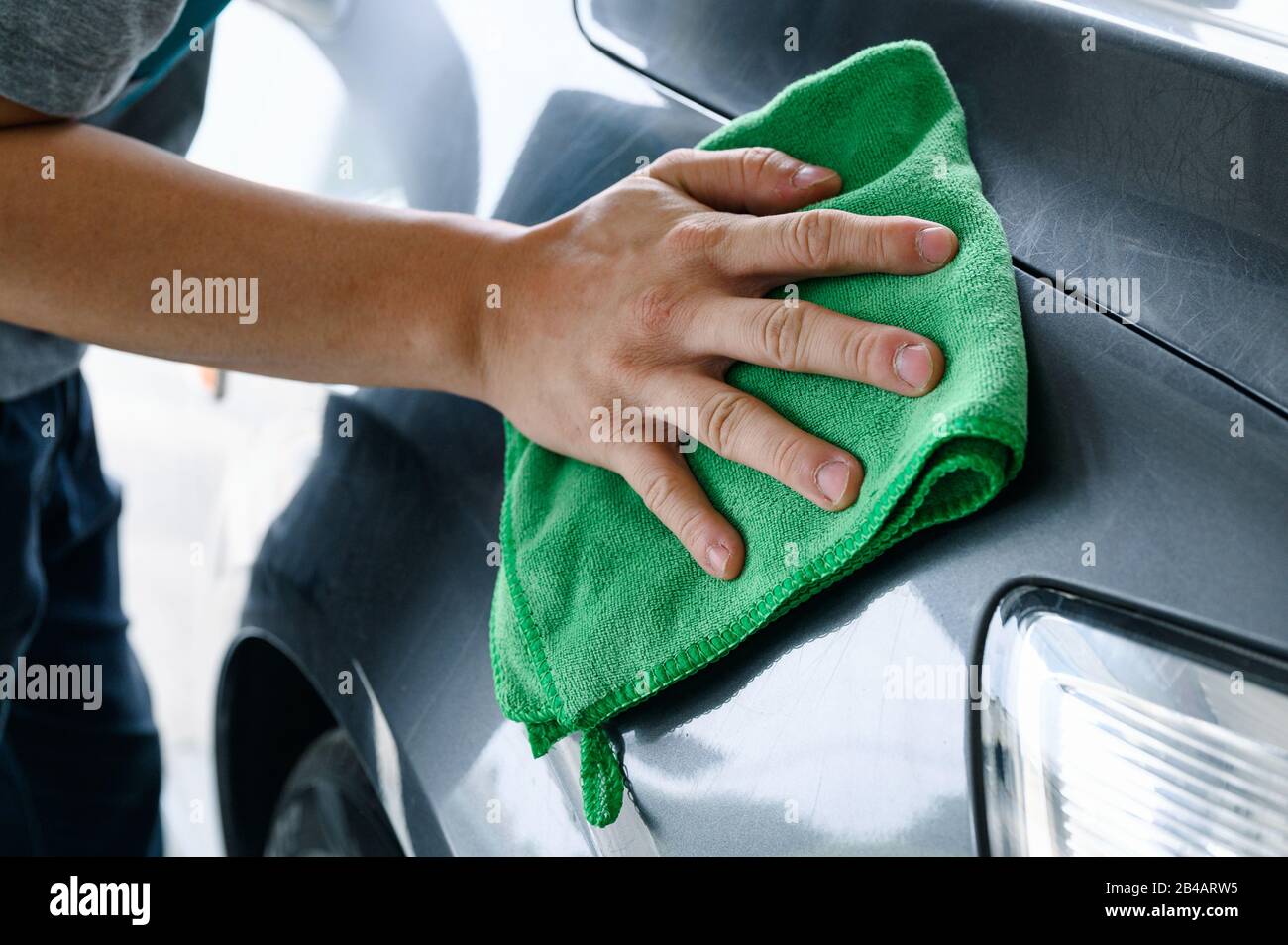 Man cleaning car with green microfiber cloth on car hood Stock Photo ...