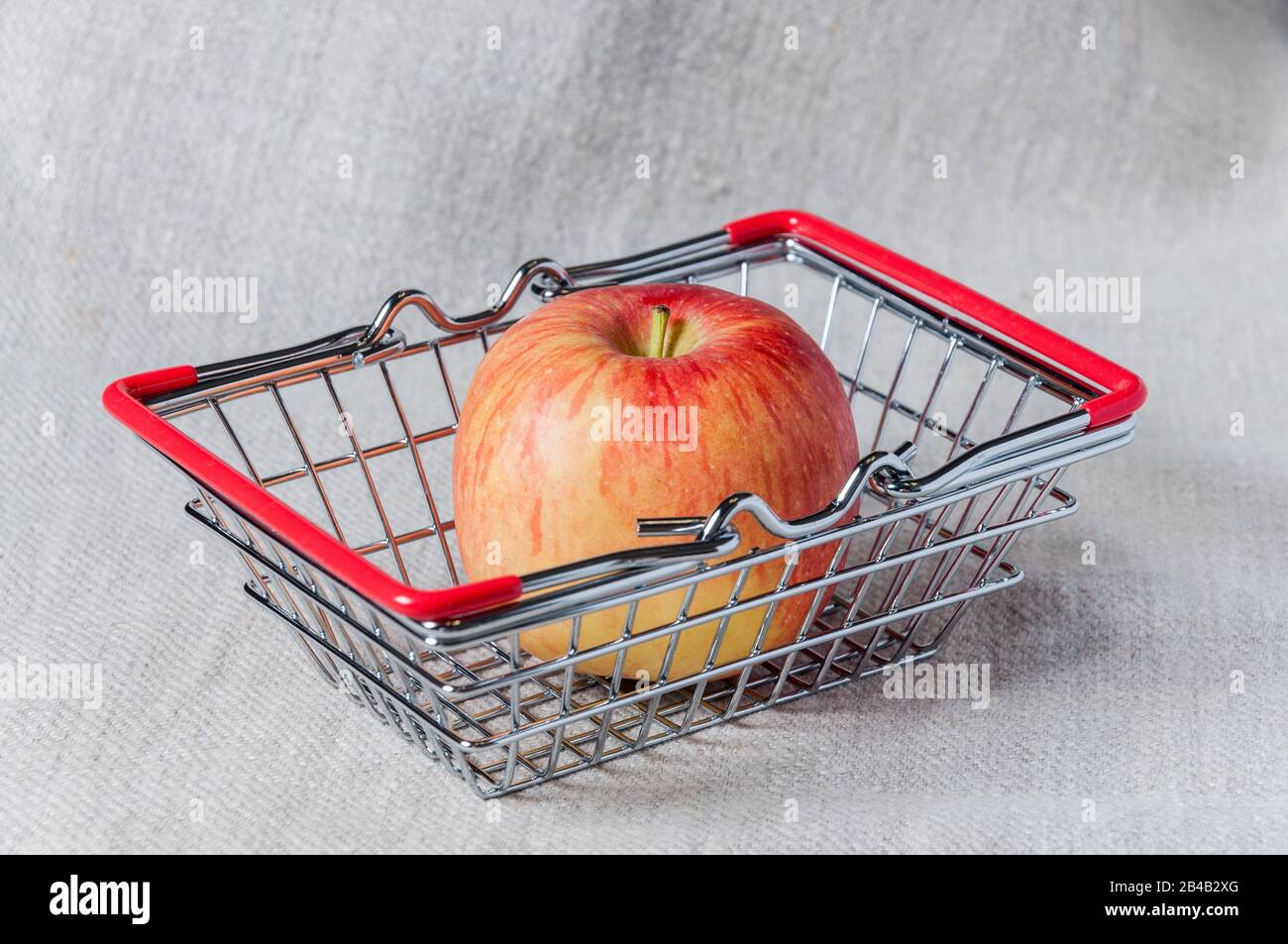 Red apple in a small shopping basket. Miniature shopping basket on ...