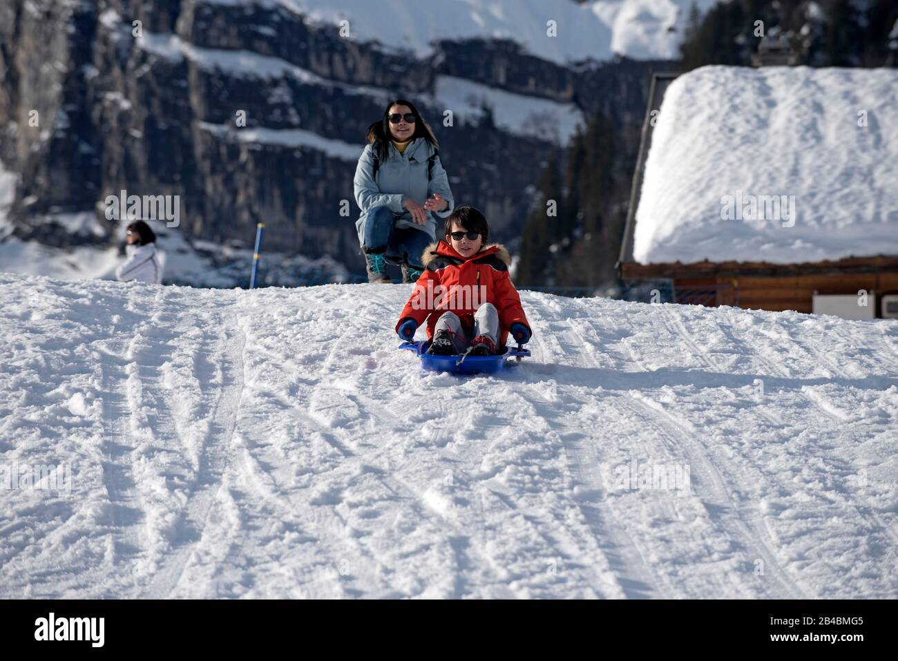 Boy on a sledge in winter with mother Stock Photo - Alamy
