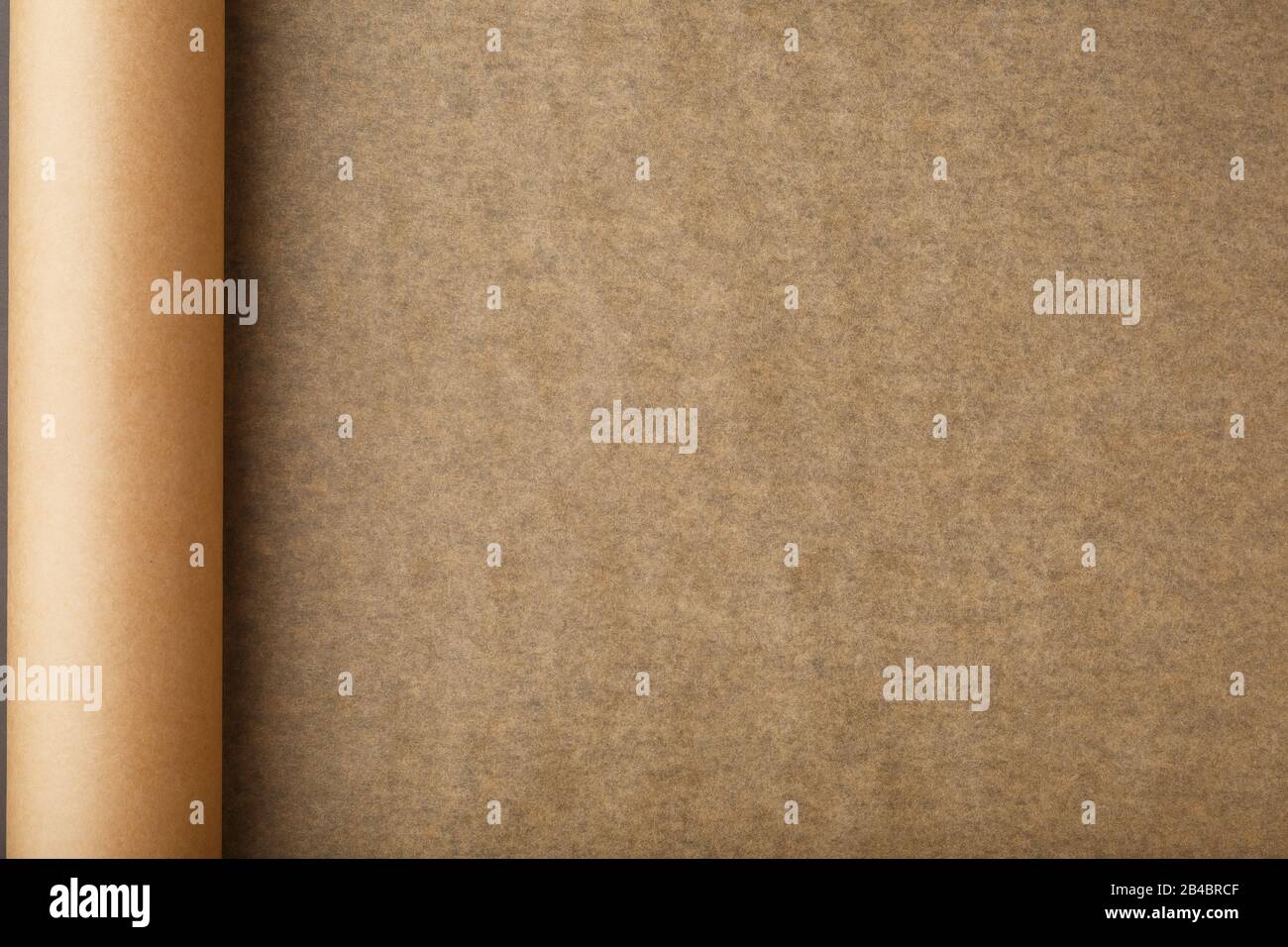A roll of unfolded brown parchment paper, for baking food in on a dark ...