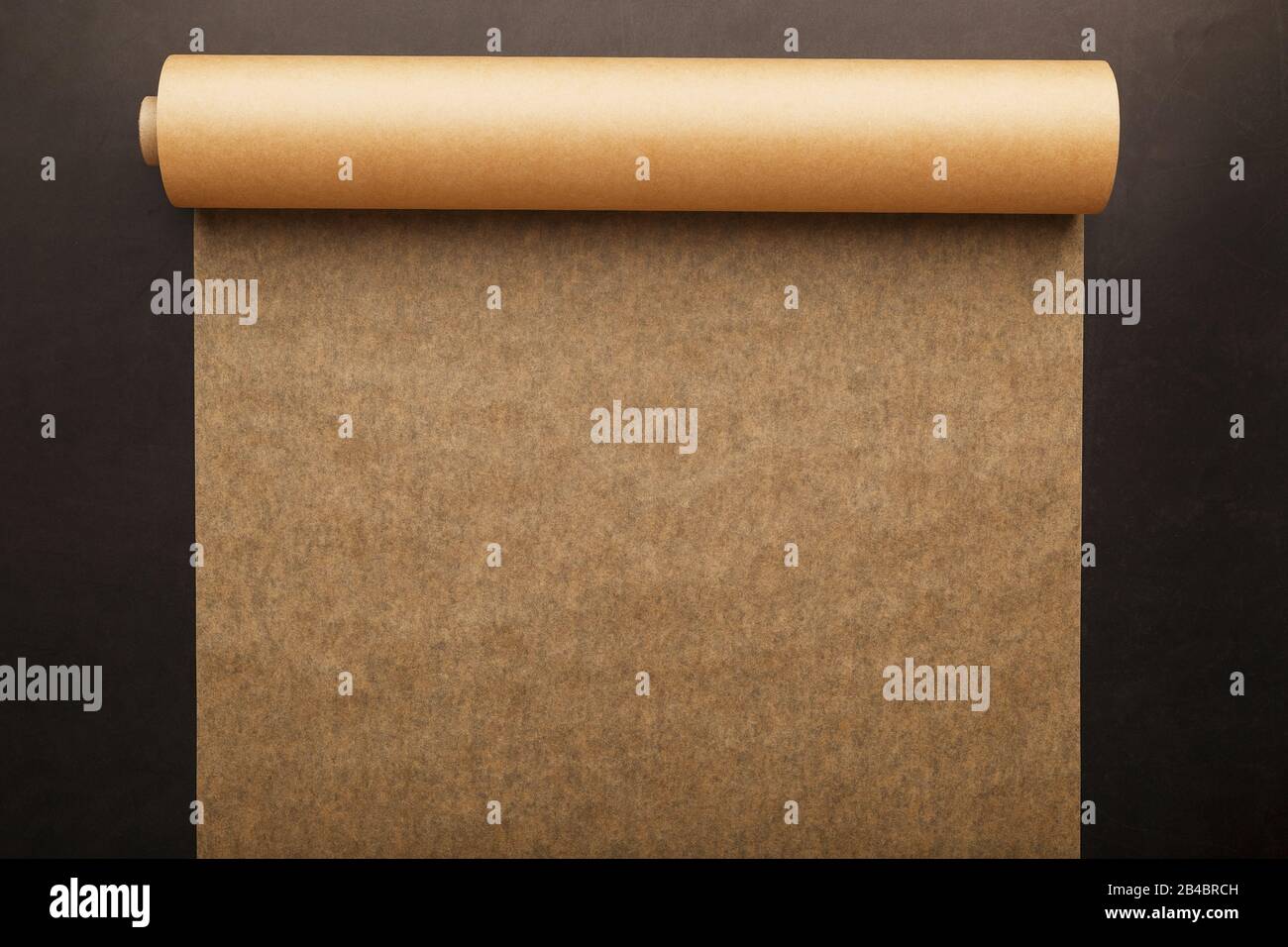 A roll of unfolded brown parchment paper, for baking food in on a dark ...