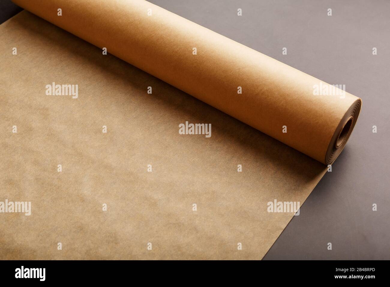 A roll of unfolded brown parchment paper, for baking food in on a dark ...