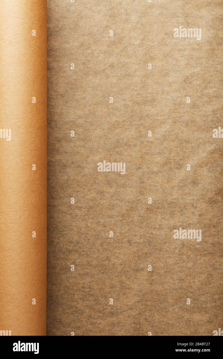 A roll of unfolded brown parchment paper, for baking food in on a dark ...