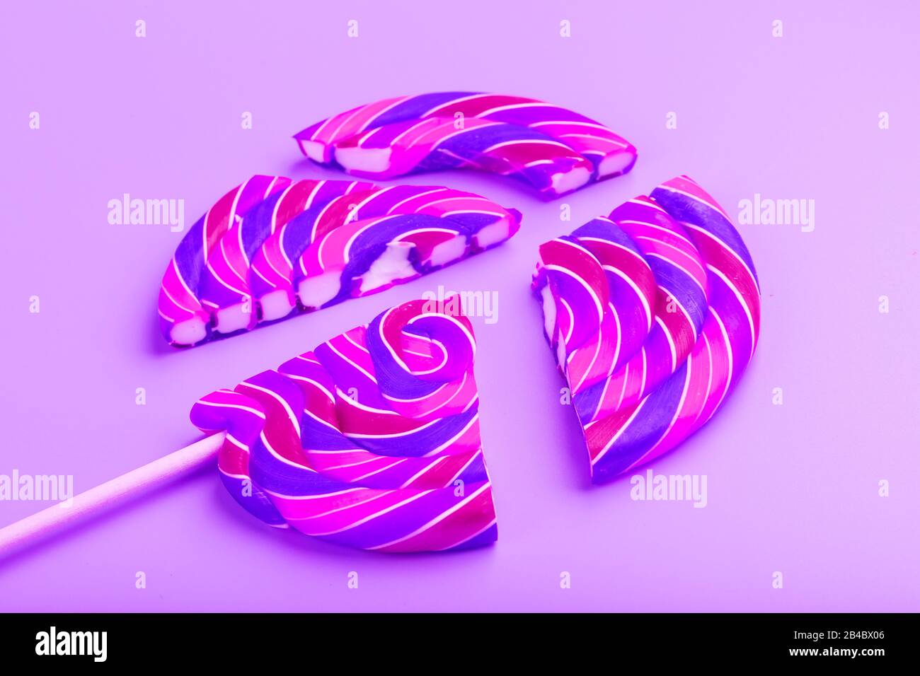Pink Lollipop split into pieces on a pink background, top view, close ...