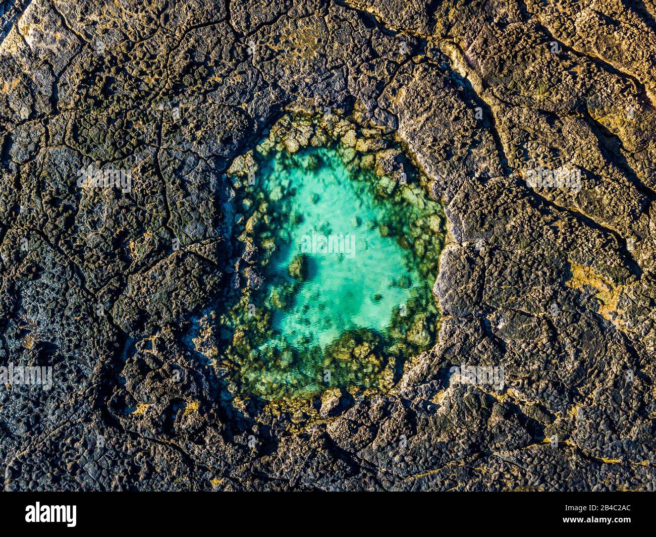 Blue natural swimming pool in the middle of black vulcanic rocks ...