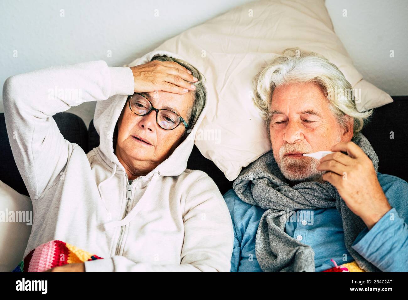 Couple of old aged senior people at home with seasonal winter cold ...