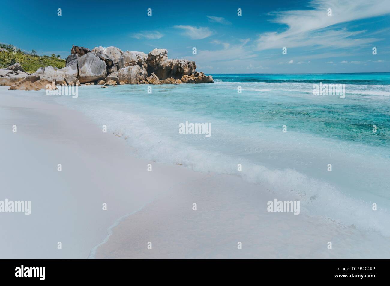 Wave on pristine blue color lagoon with granite rocks on Anse Coco ...