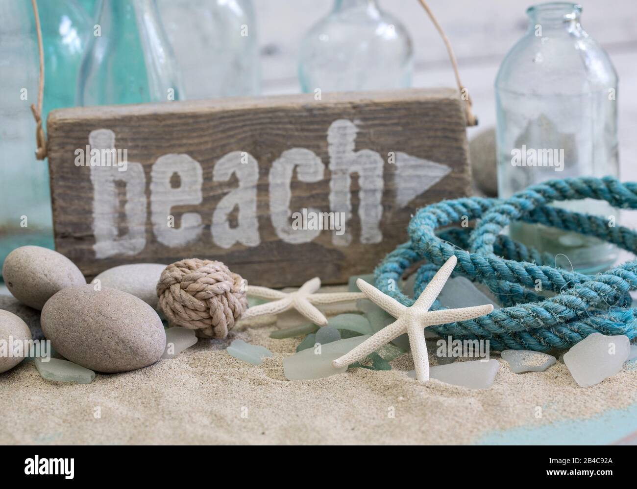 Nautical still life with wooden beach sign, rope, pebble and old blue ...