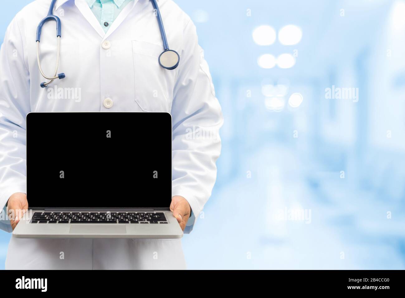 Doctor holding laptop computer in straight front view with blurred ...