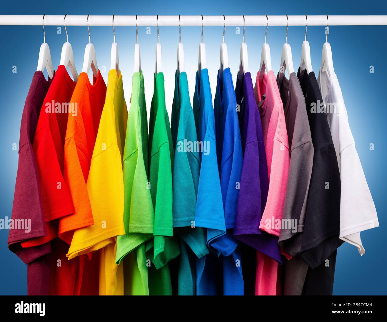 row of many fresh new fabric cotton t-shirts in colorful rainbow colors ...