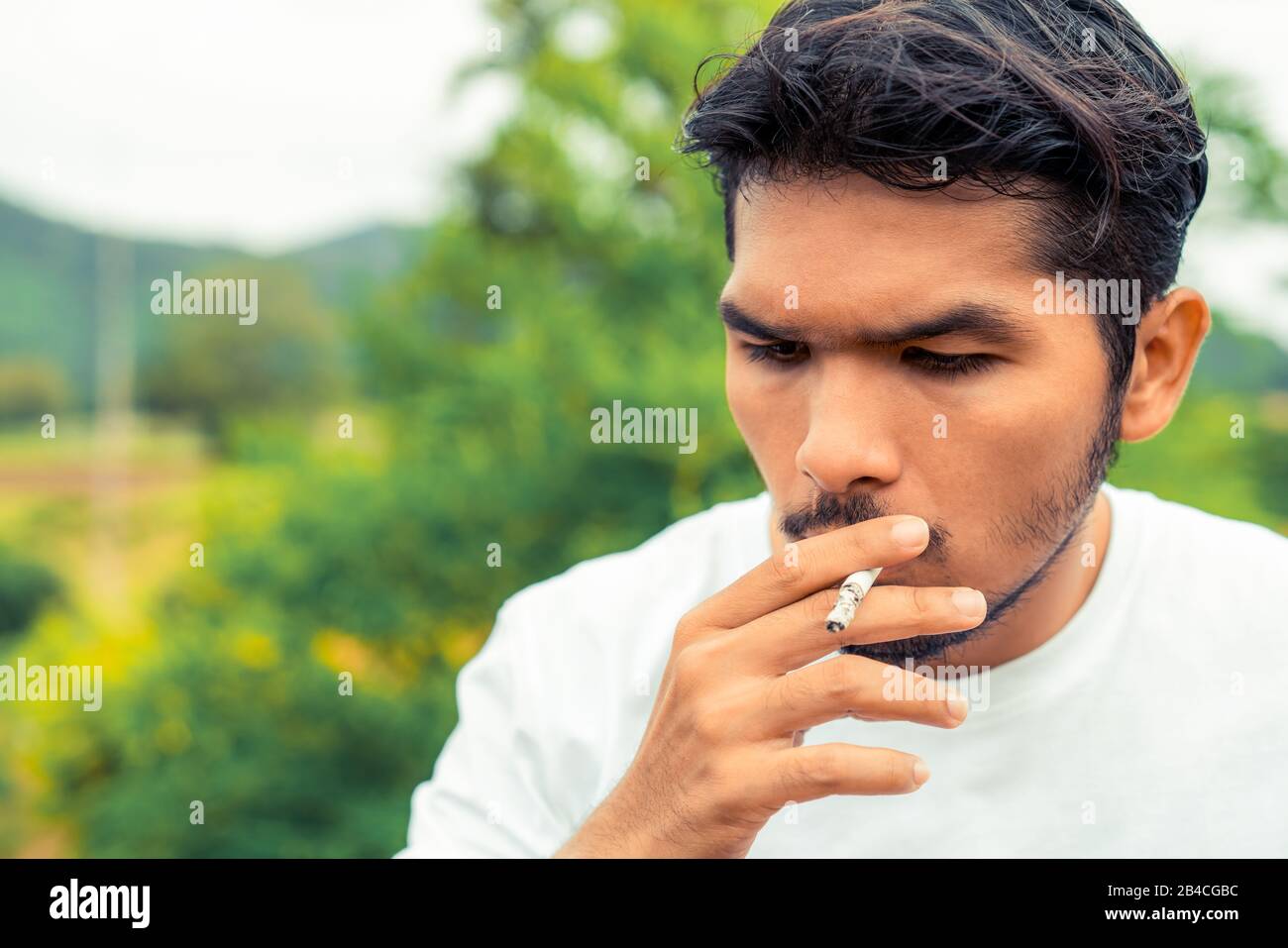 Young man smoking cigarette in the outdoors and nature background Stock ...