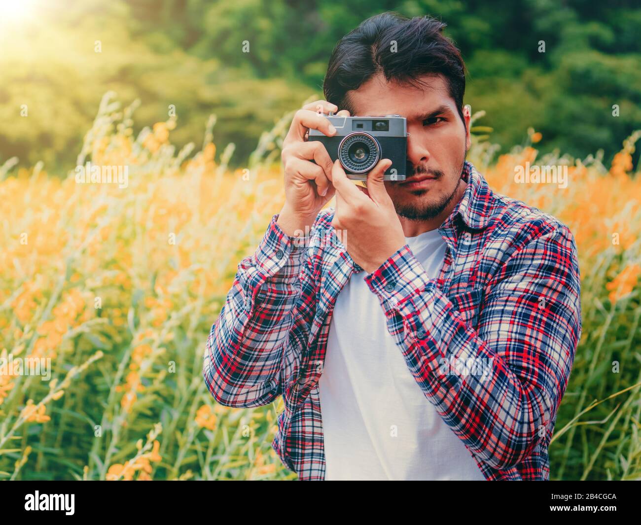Young hipster man taking photo with old style camera with nature ...
