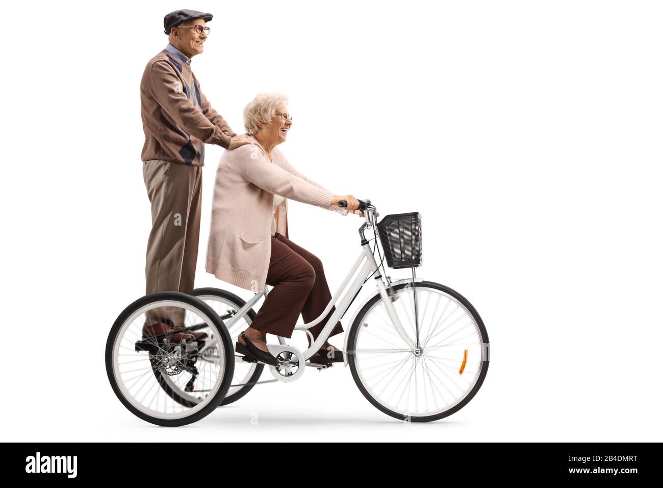 Senior woman riding a tricycle and a senior man standing behindd and ...