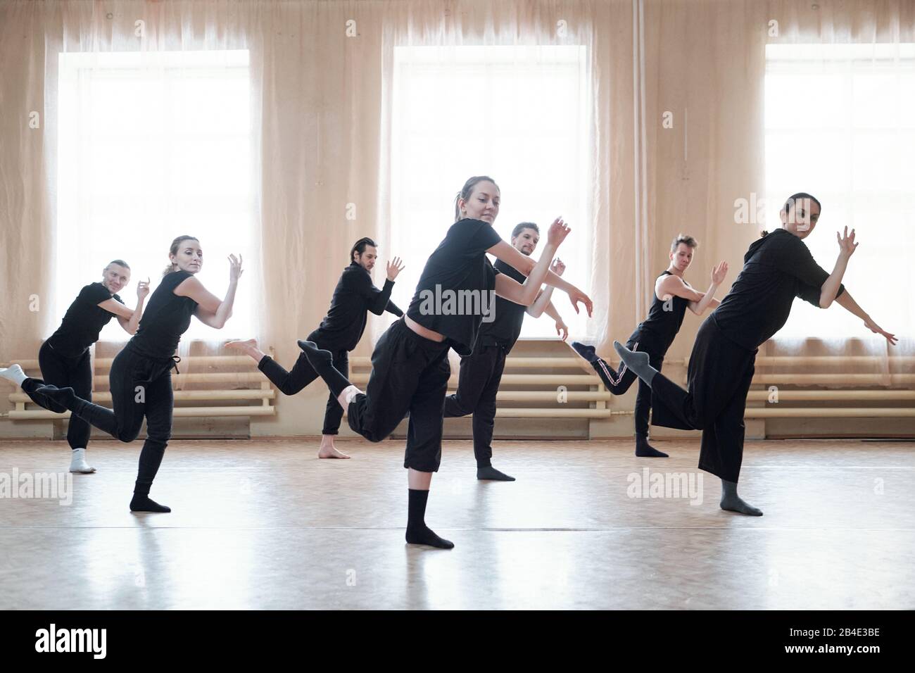 Seven young active men and women in black sportswear standing on the ...